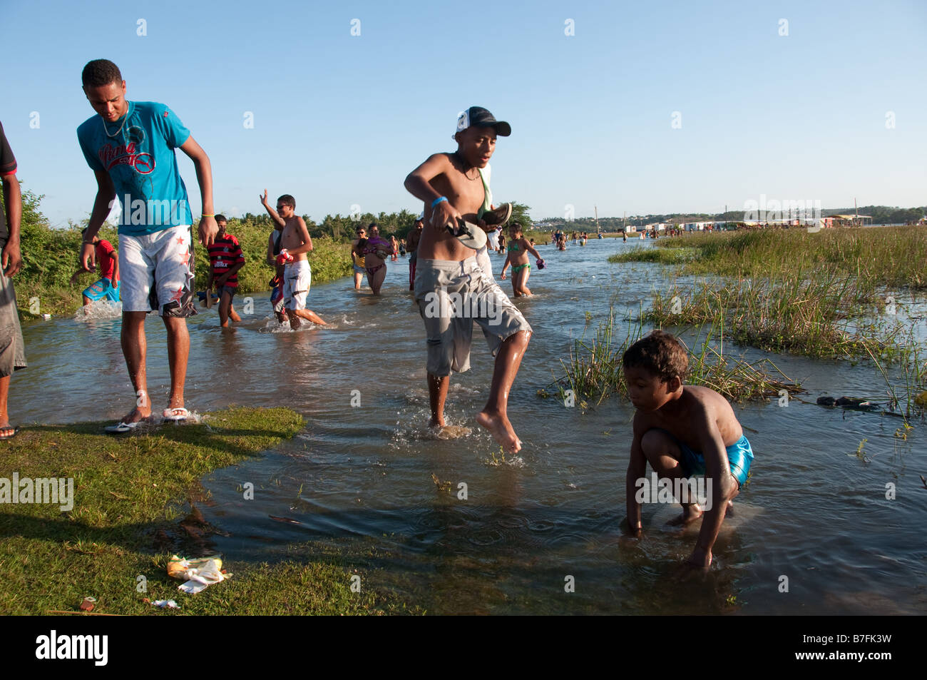 People walk through water to reach a river beach with a small number of ...