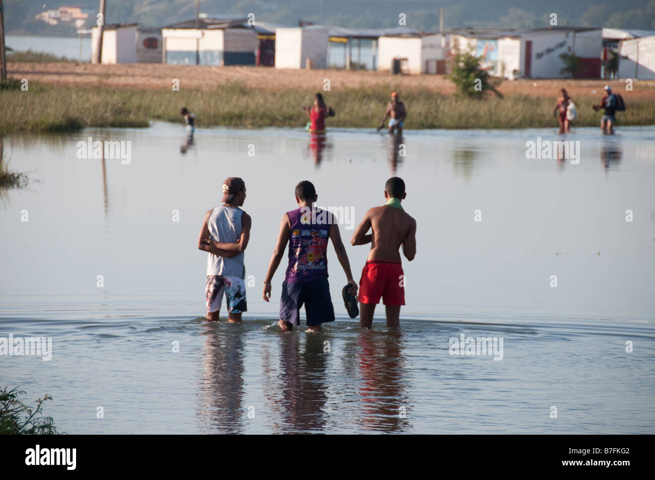 Three boys walk towards the beach People walk through water to reach a ...