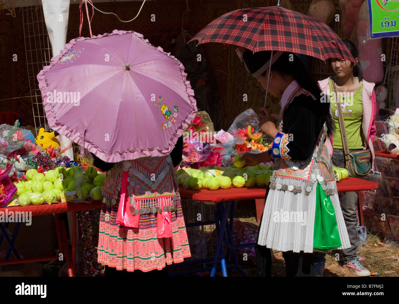 Two Hmong girls, in traditional costume, are browsing at a stall ...