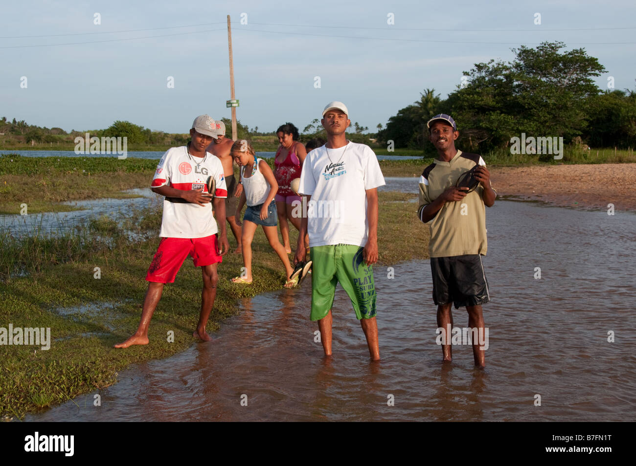 People walk through water to reach a river beach with a small number of ...