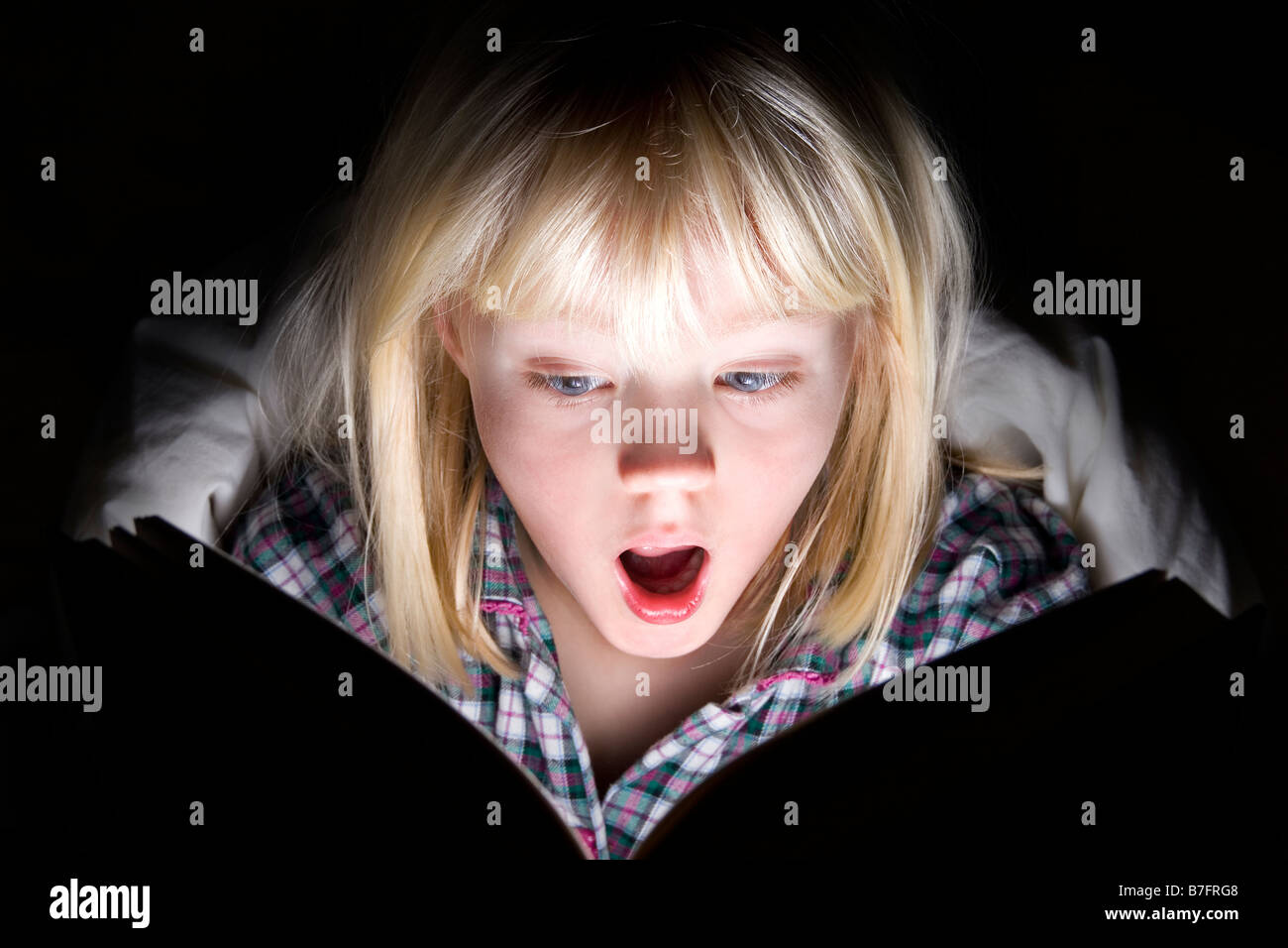 young female reading in bed at night by torchlight Stock Photo - Alamy