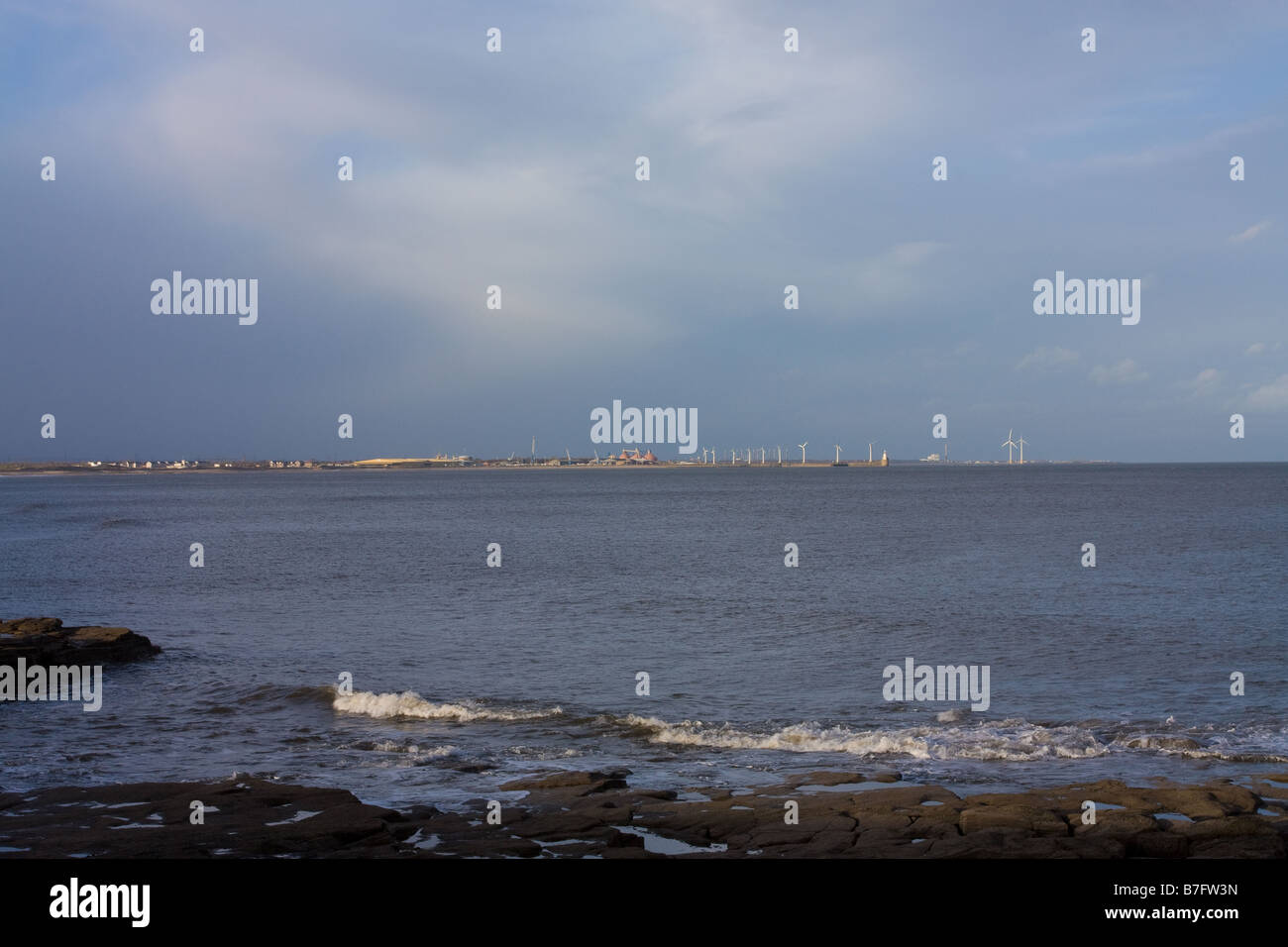 Surf breaking over rocks at Seaton Sluice with Blyth beach and surfers ...