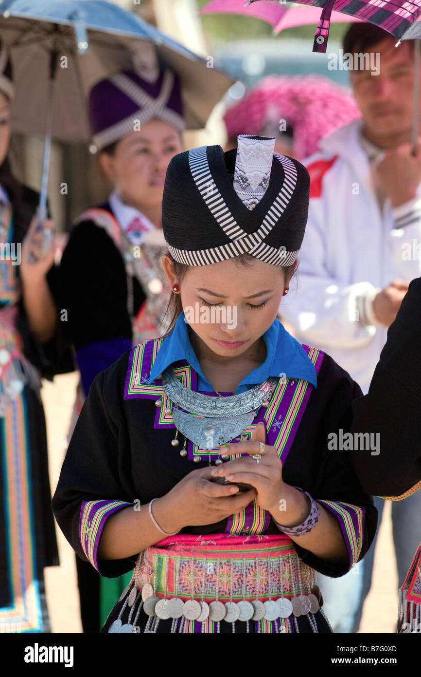 A Hmong girl in traditional dress texts on her mobile phone under the ...