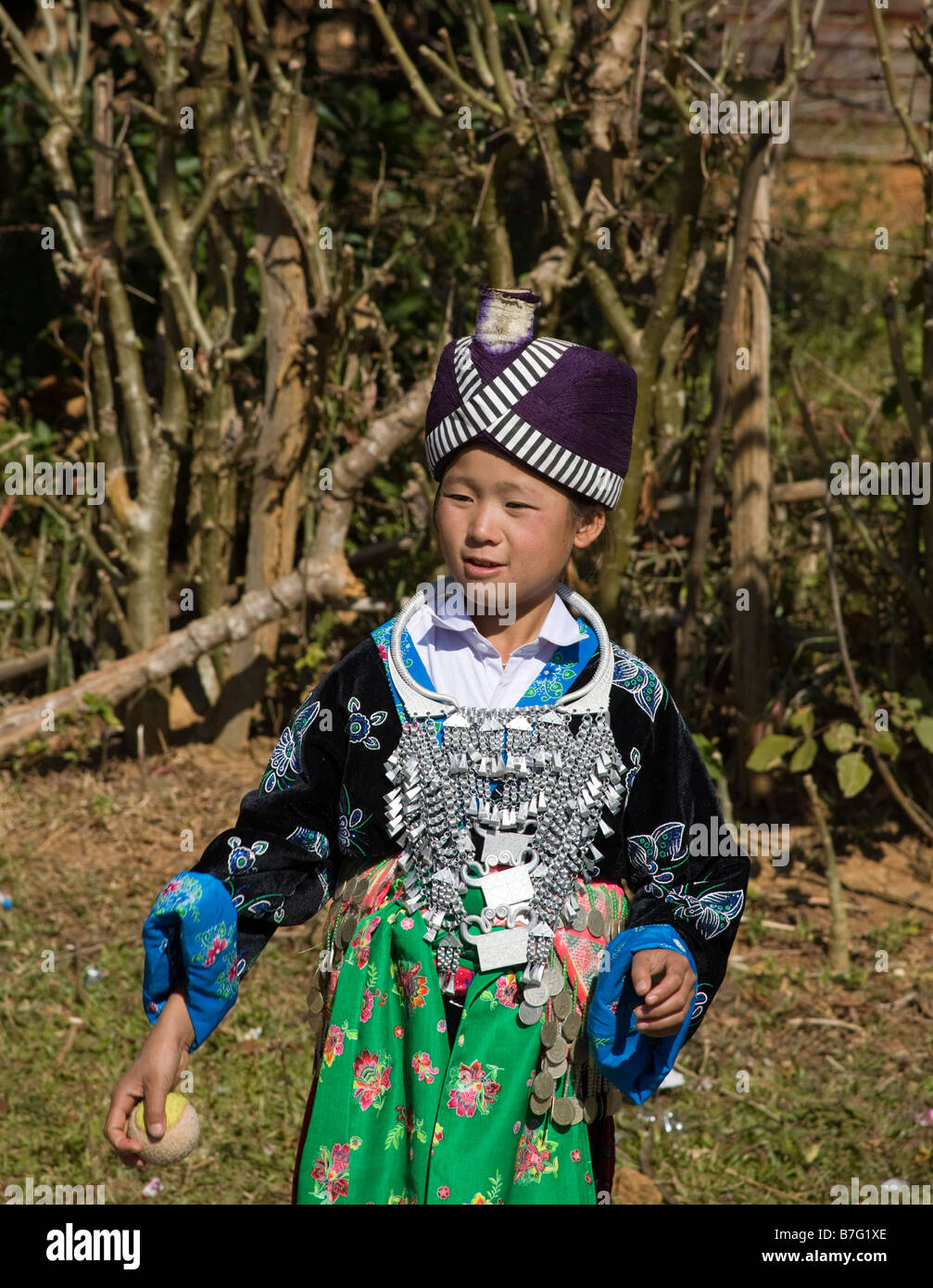 A Hmong girl, in traditional dress, plays ball at a ball throwing game ...