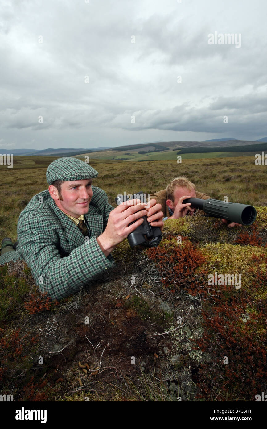 Stalkers using binoculars and telescope to spot deer on hills in ...