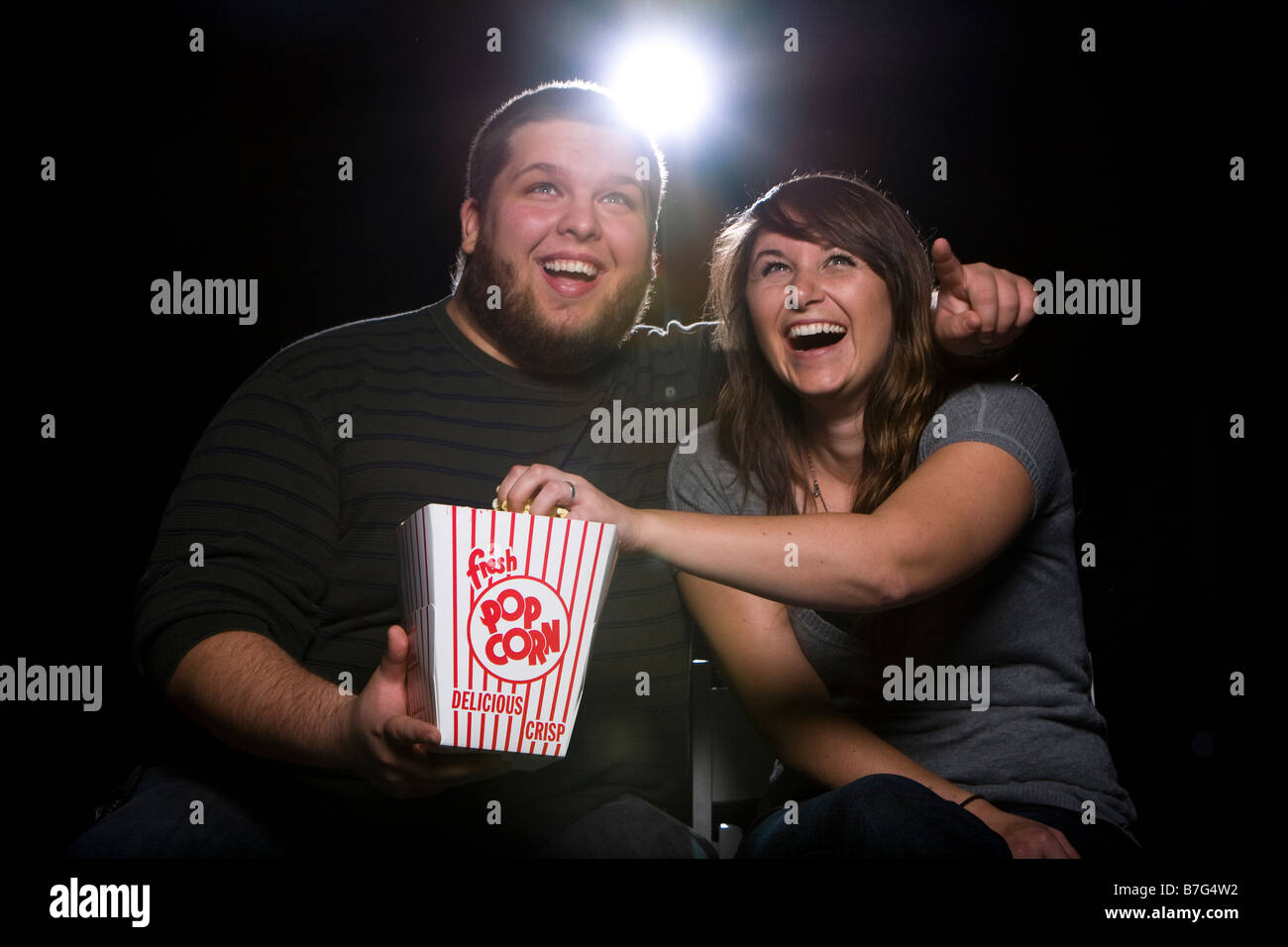 A young couple at the movies laugh and eat popcorn Stock Photo - Alamy