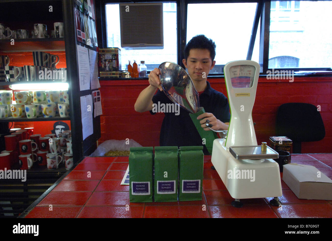 A man weighing and measuring tea leaves for sale Stock Photo - Alamy