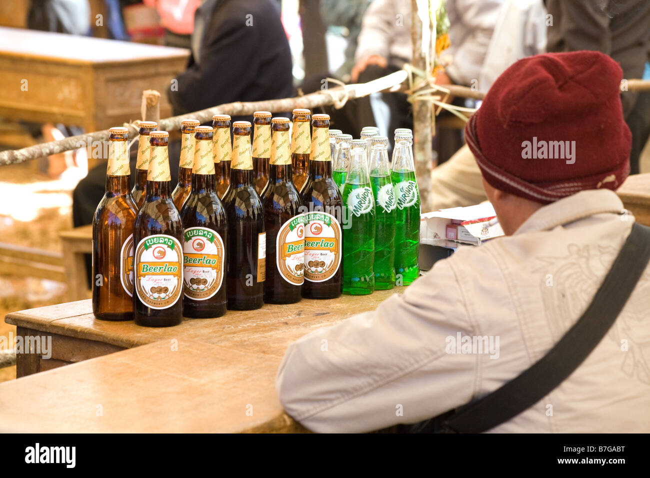 A man sits looking at a collection of empty Beer Lao and Miranda ...