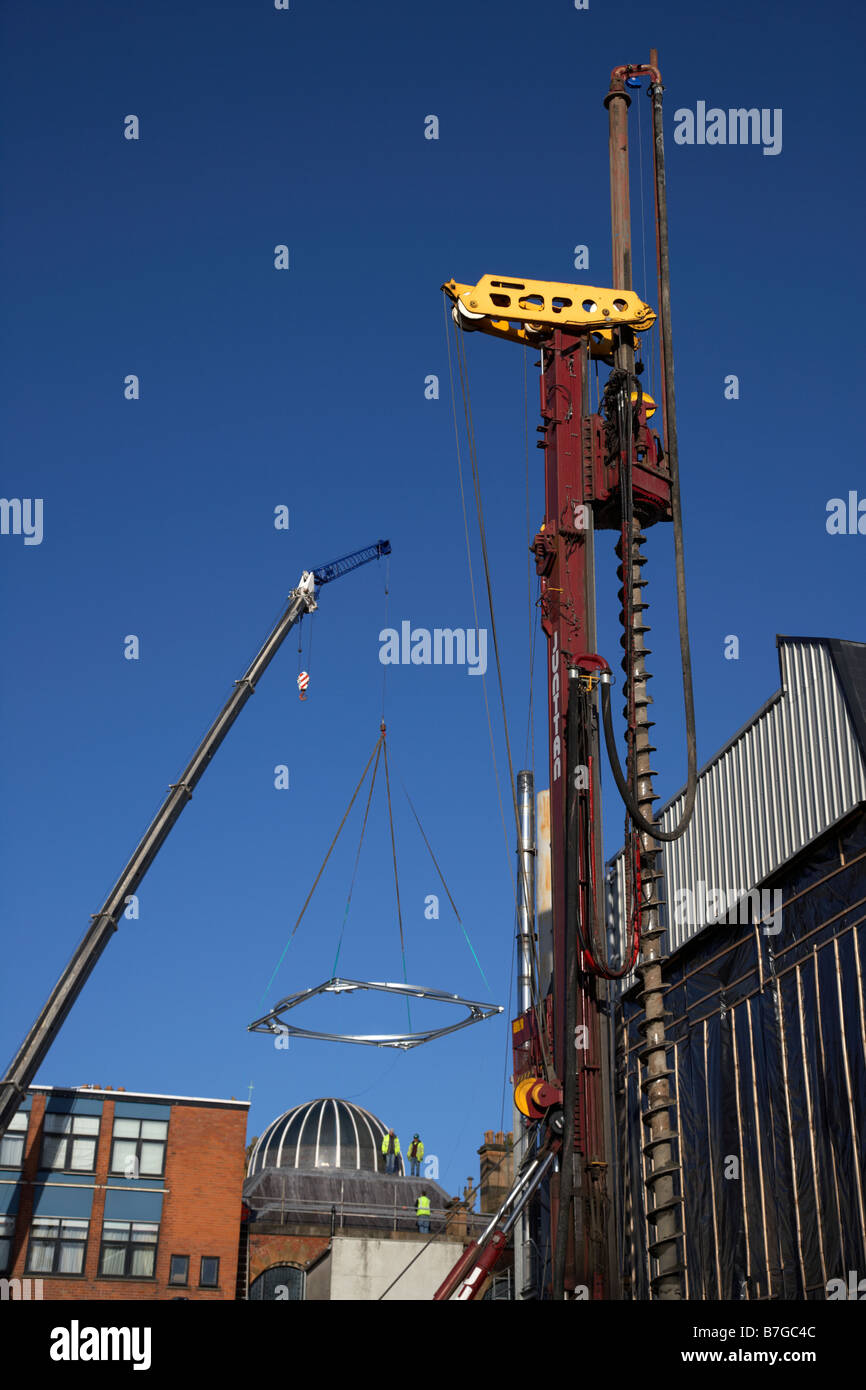 Screw auger piling rig and crane lifting framework into place on a ...