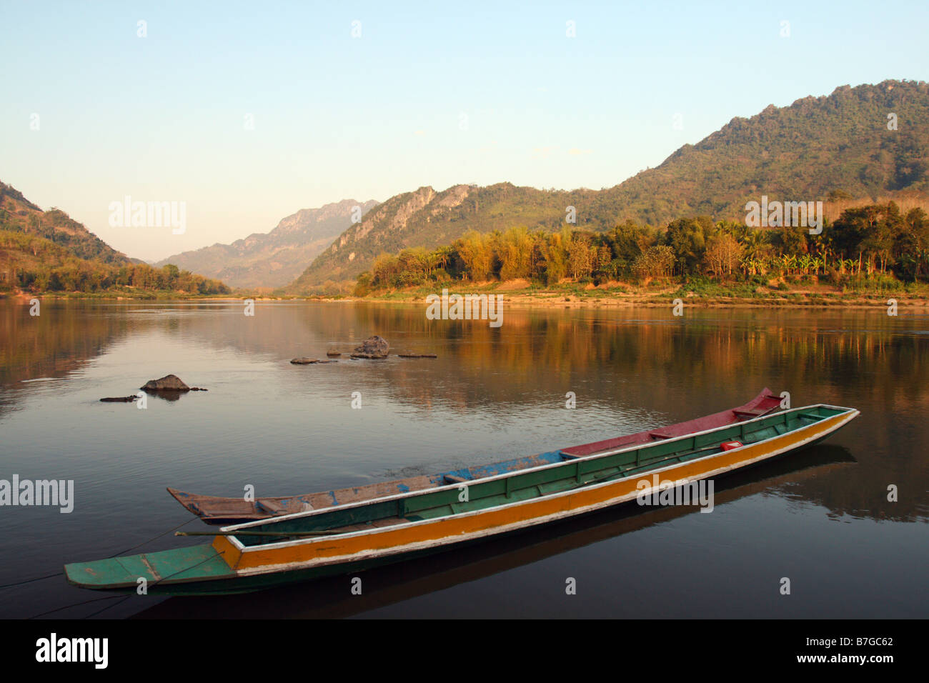 Traditional long boat at river side. Sunrise Laos Stock Photo - Alamy