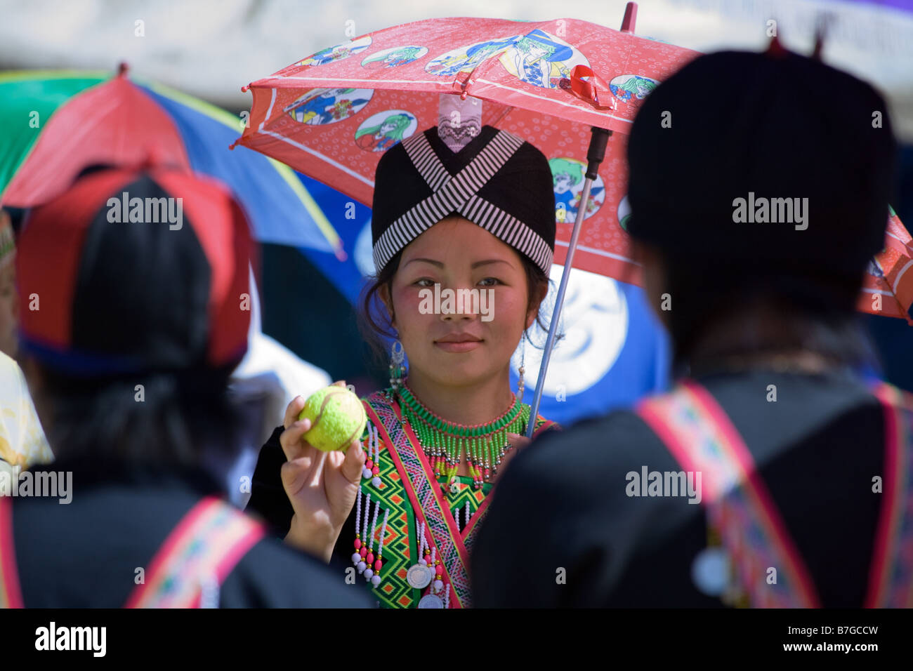 A Hmong girl in traditional costume catches a ball at a Hmong New Year ...