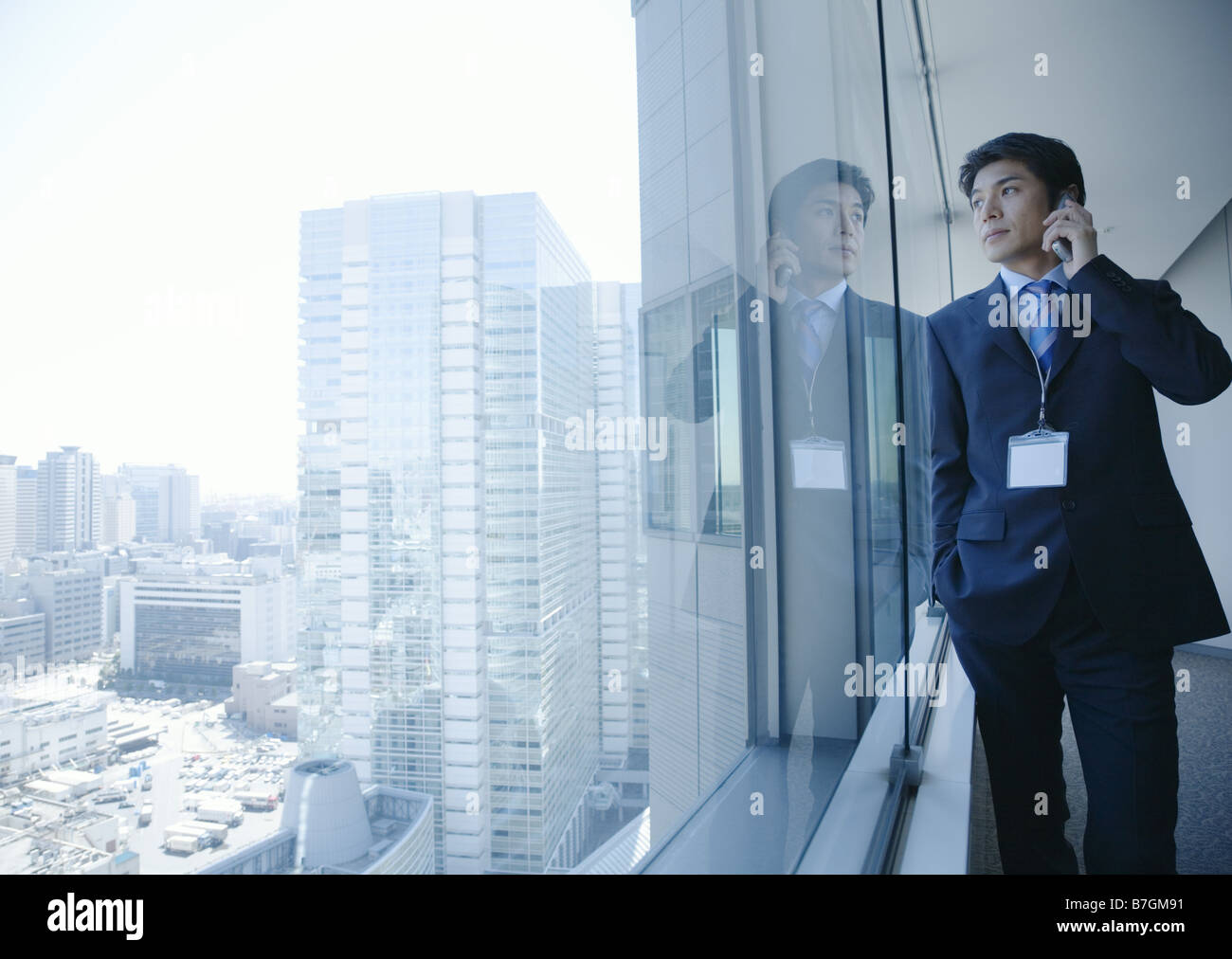 Man on phone looking out window Stock Photo - Alamy