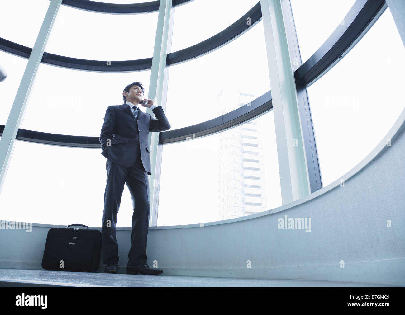 Man on phone looking out window Stock Photo - Alamy