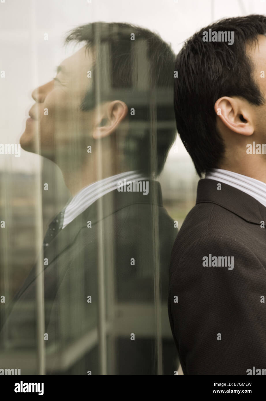 Businessman leaning against wall Stock Photo - Alamy
