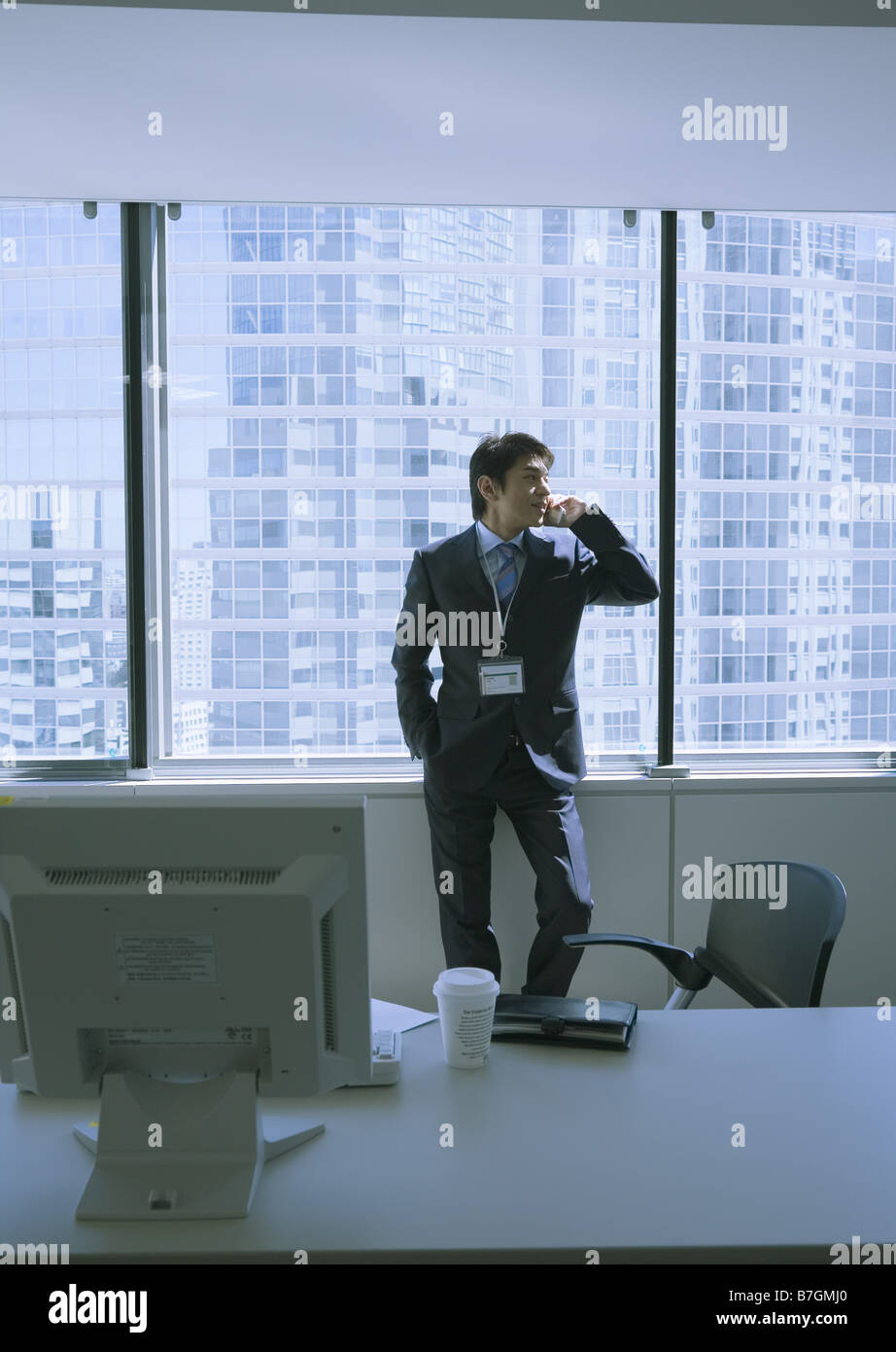 Man on phone looking out window Stock Photo - Alamy