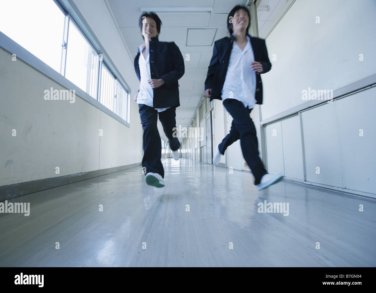 Two young schoolboys running in corridor Stock Photo - Alamy