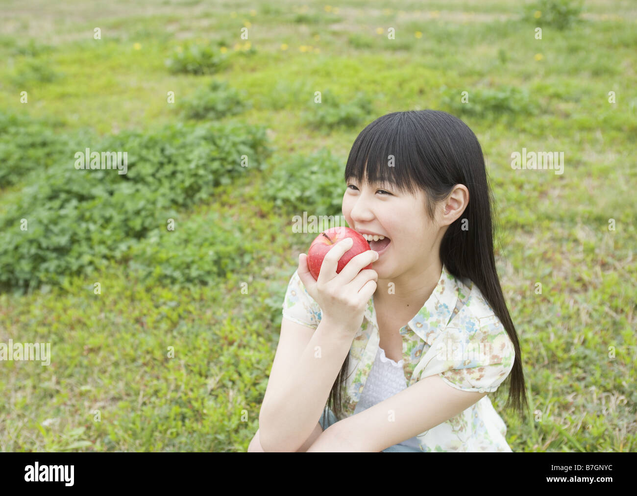 Girl eating an apple in the field Stock Photo - Alamy