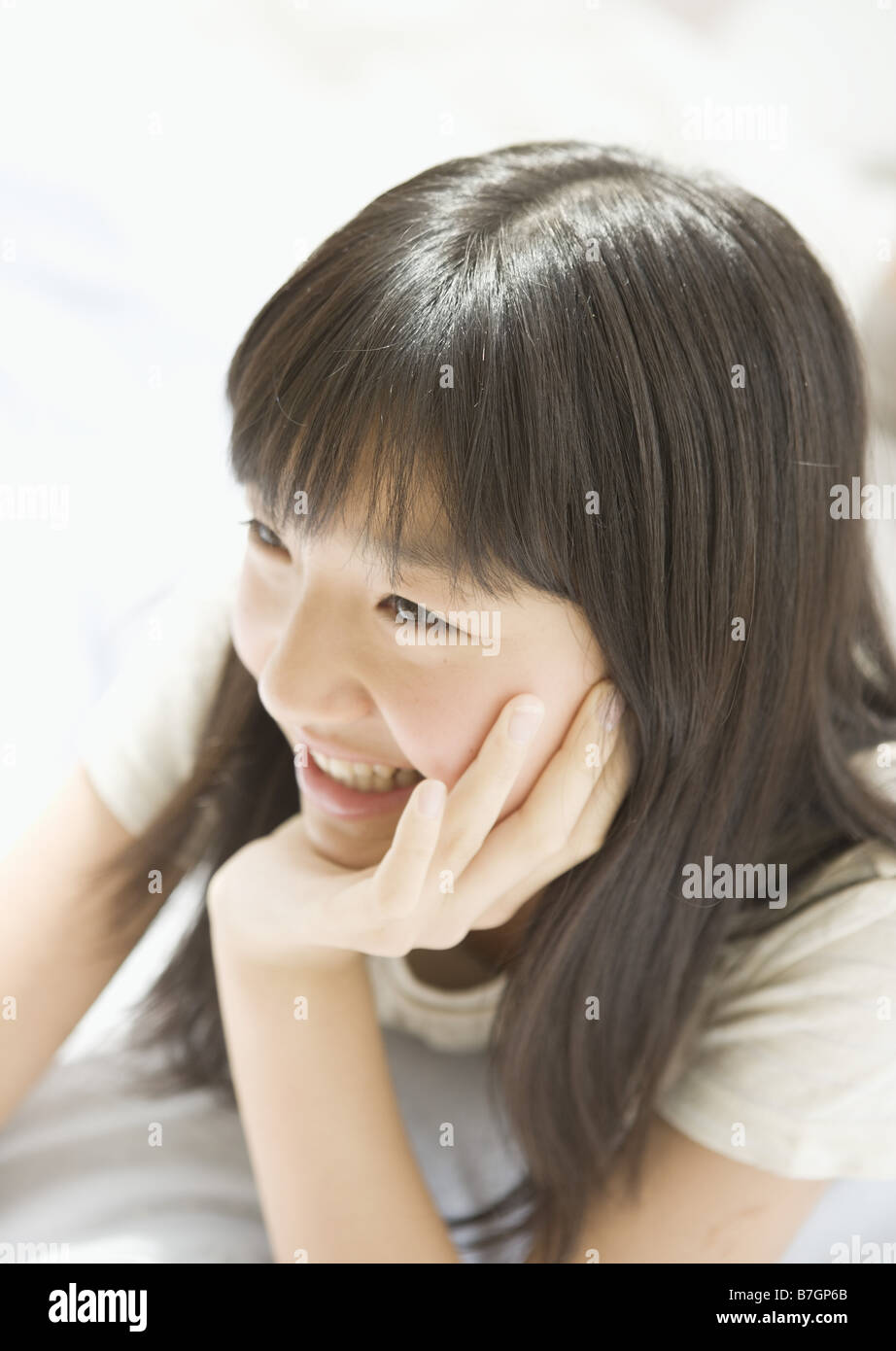 Smiling girl resting her cheek on her hand in the room Stock Photo - Alamy