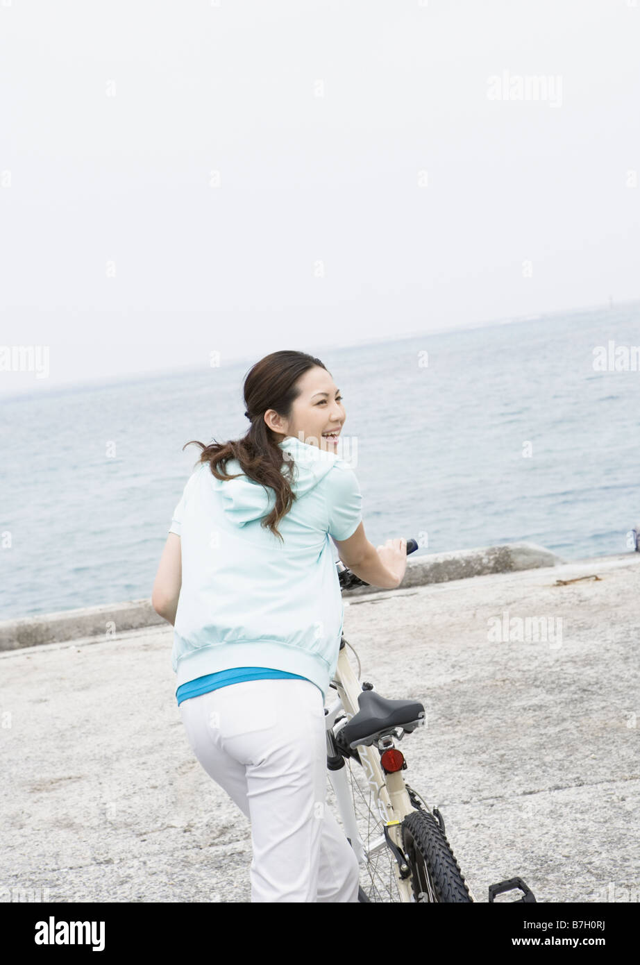 A young woman pushing bicycle Stock Photo - Alamy