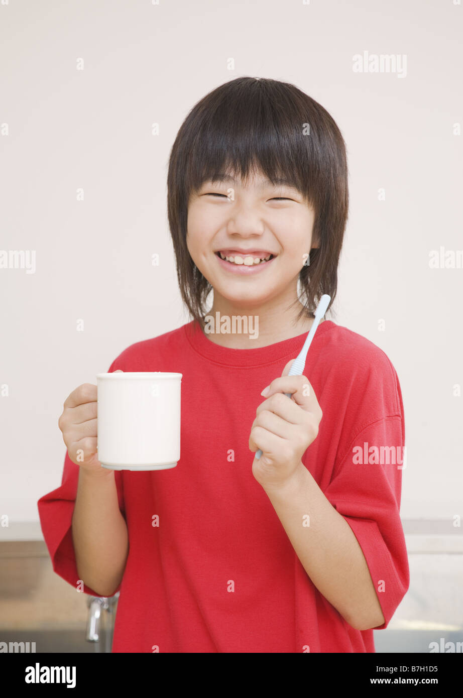 Elementary school boy holding toothbrush and cup Stock Photo - Alamy