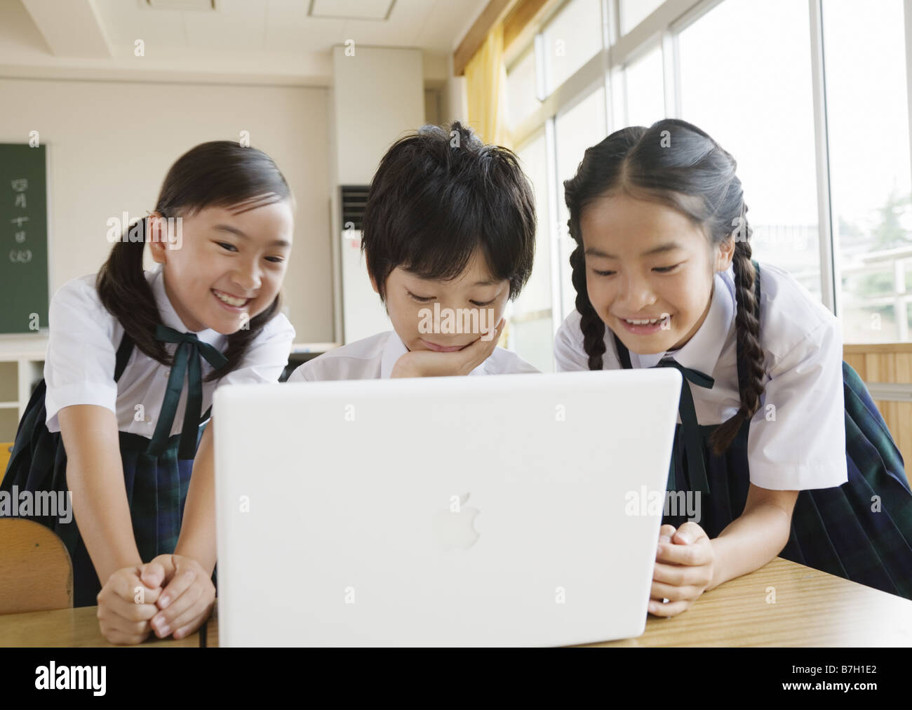 Elementary school students looking at laptop Stock Photo - Alamy