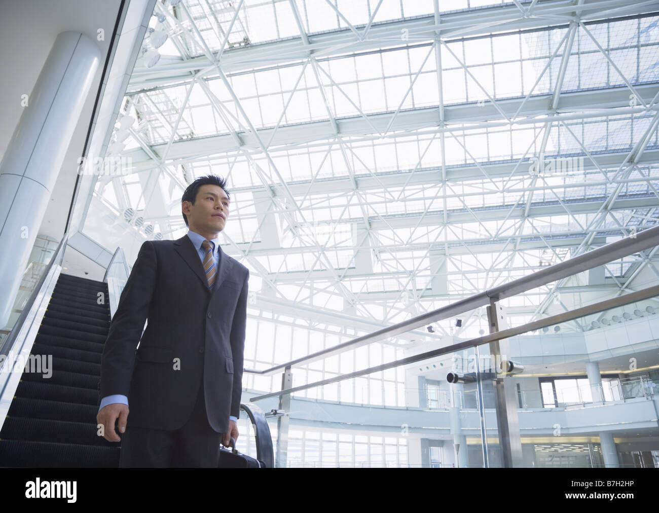 Businessman stepping off escalator Stock Photo - Alamy