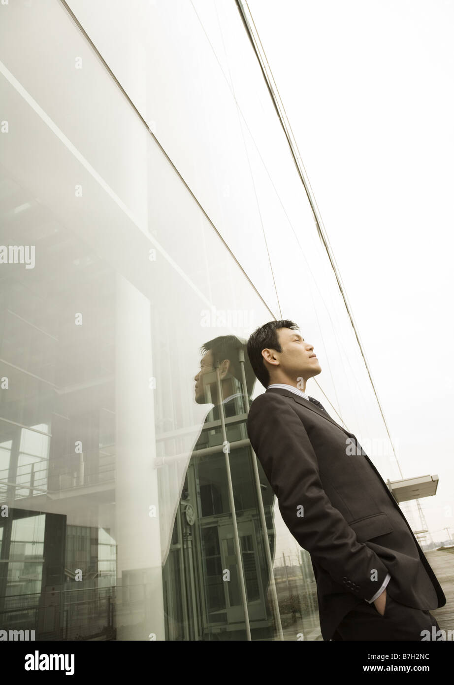 Businessman leaning against wall Stock Photo - Alamy
