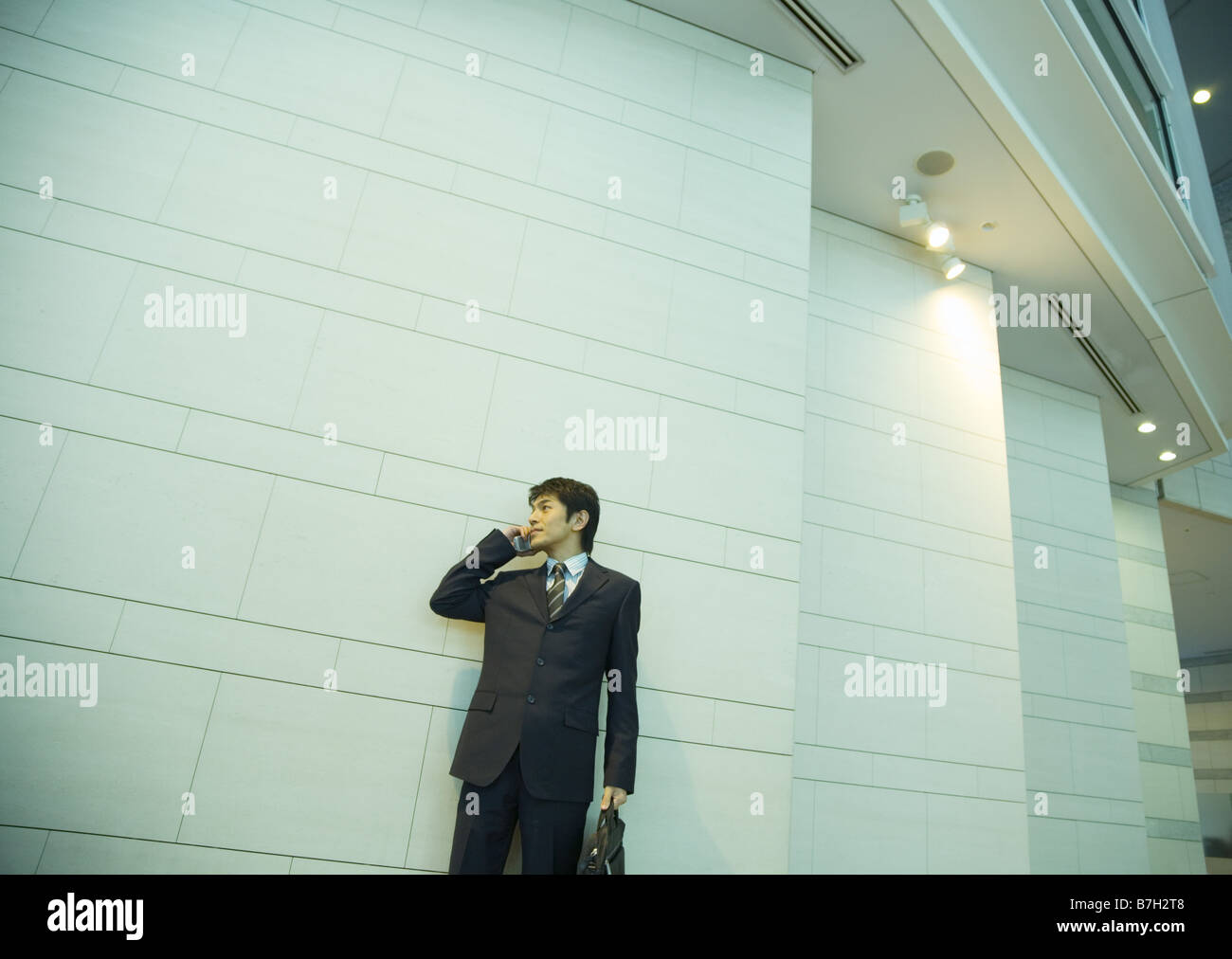 Man on cell-phone by wall Stock Photo - Alamy
