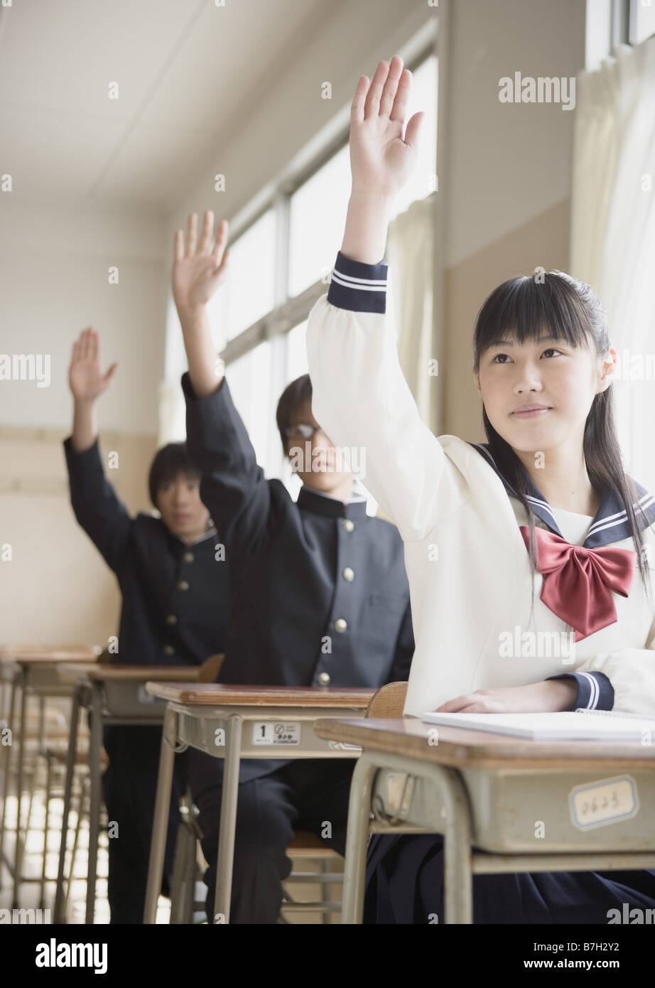 Students raising hands in classroom Stock Photo - Alamy