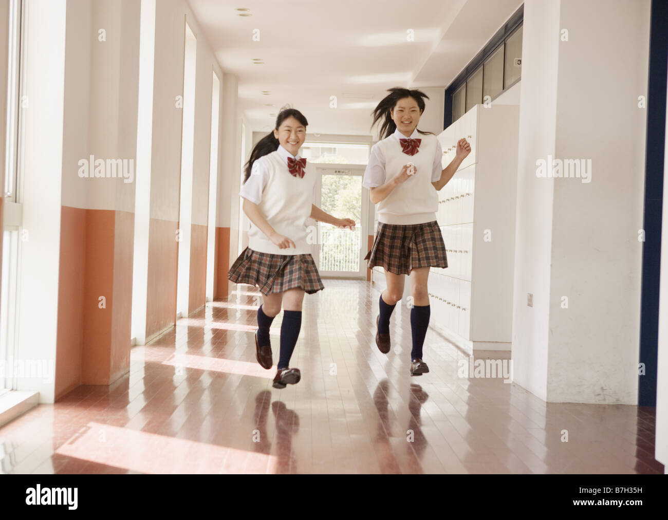 Two schoolgirls running in corridor Stock Photo - Alamy