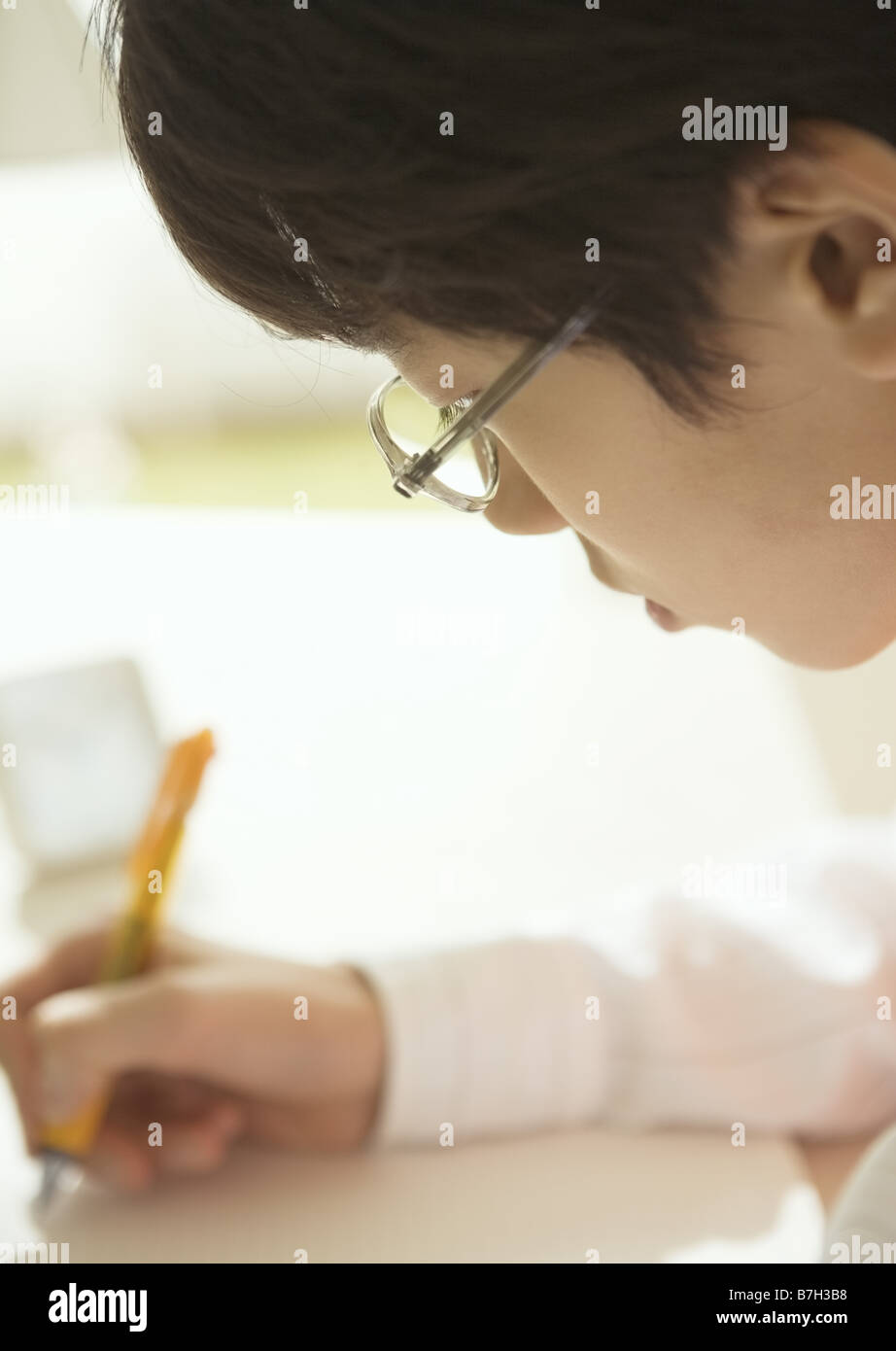 Boy, wearing his glases, studying by himself at the desk Stock Photo ...