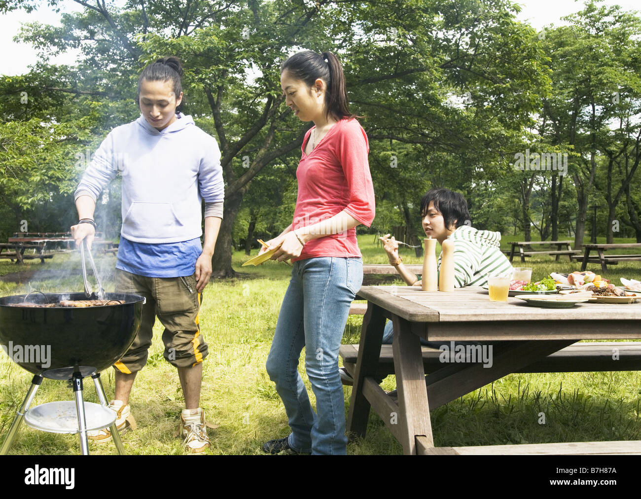 Young people barbecuing Stock Photo - Alamy