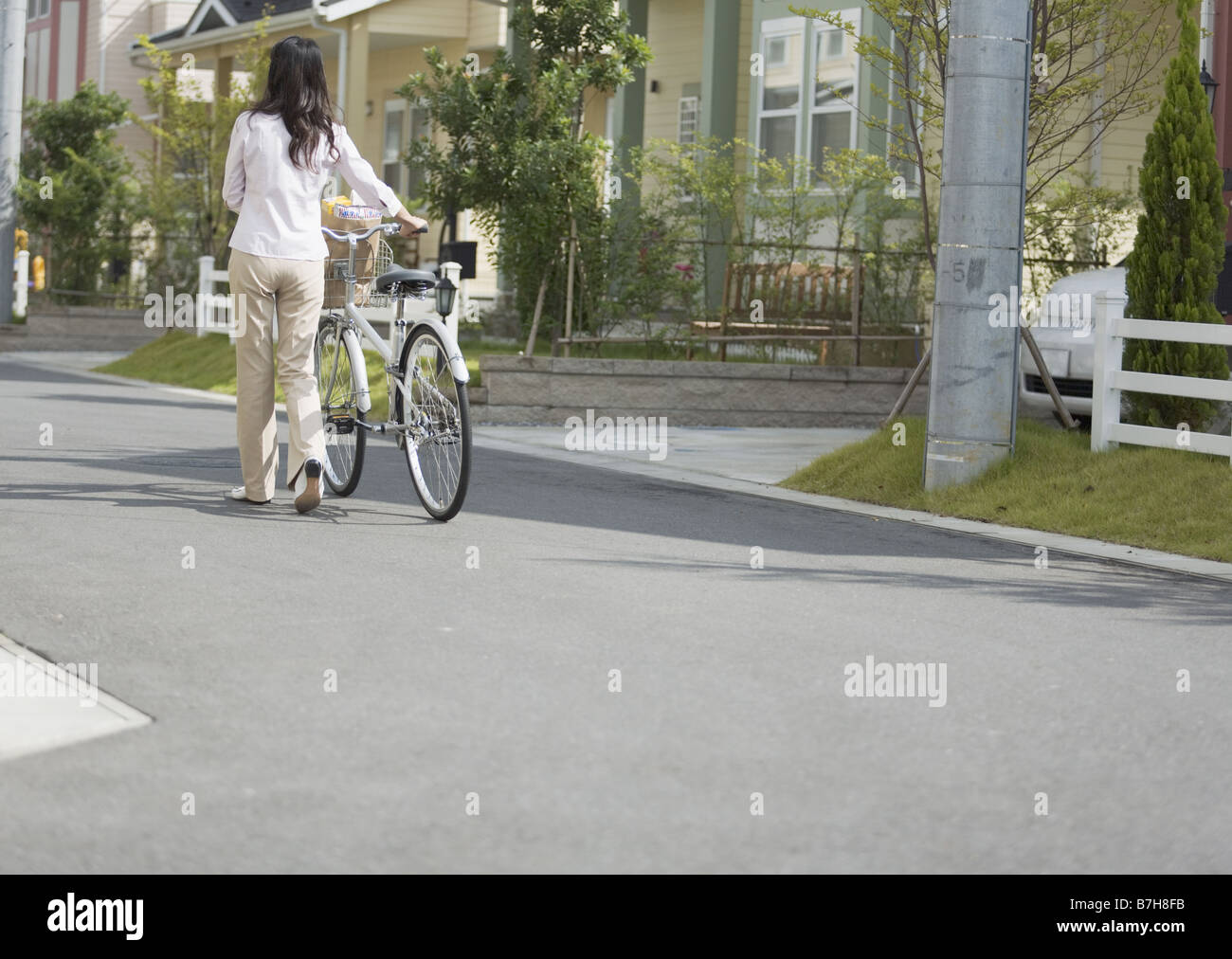 Woman wheeling a bicycle Stock Photo - Alamy