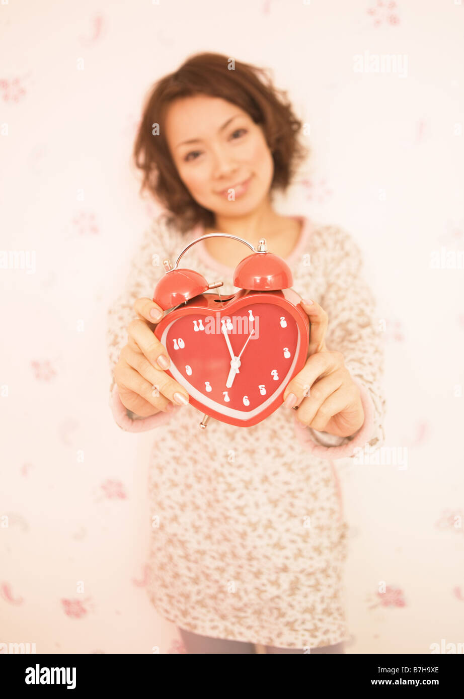 A woman holding alarm clock Stock Photo - Alamy