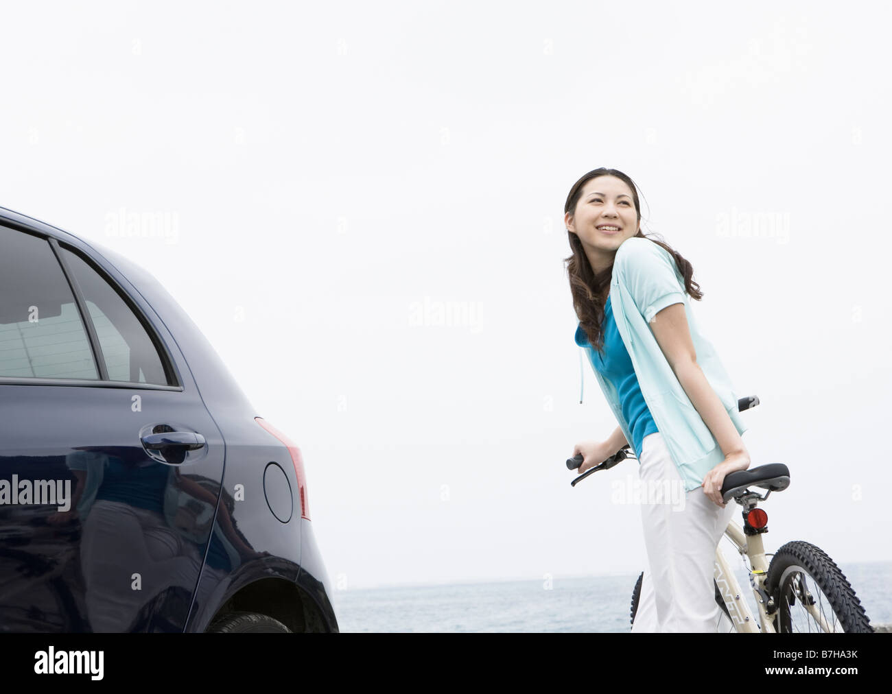 A young woman leaning against bicycle Stock Photo - Alamy