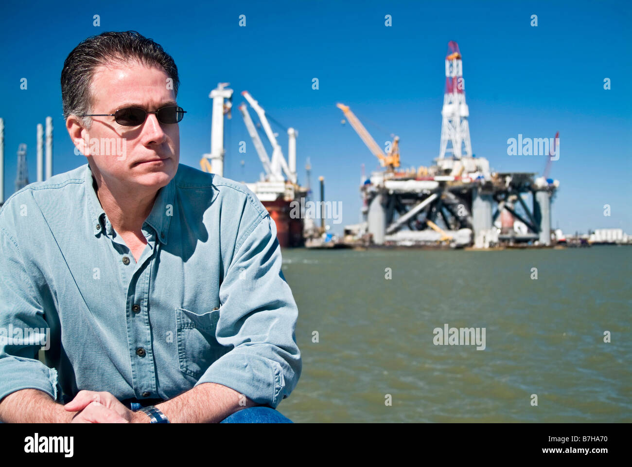 A man with drilling rigs behind him in the distance Stock Photo - Alamy