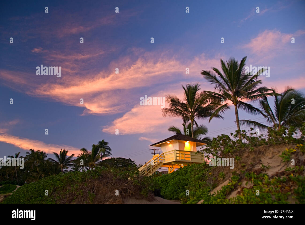 lifeguard shack and tropical foliage with sunset colored clouds Stock ...