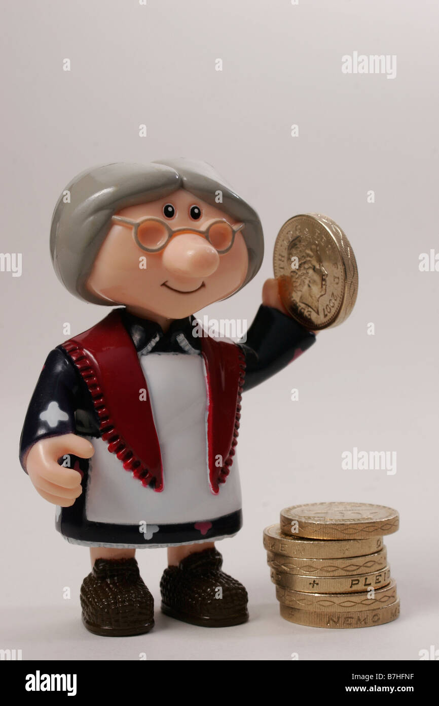 Model character of old lady holding a pound coin beside a small pile of ...