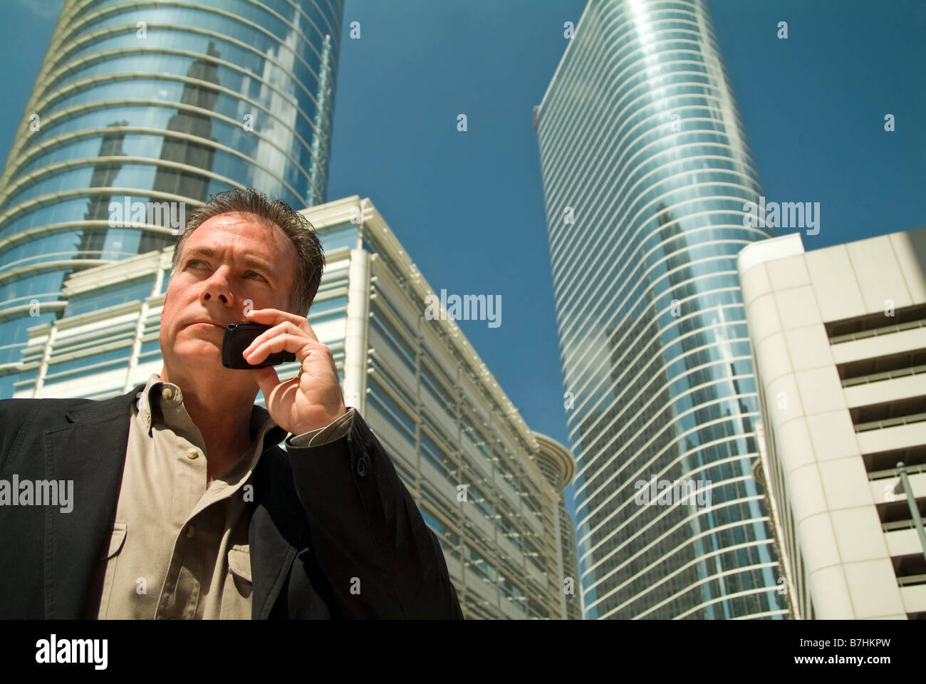 A man standing in front of some some towering office building talking ...