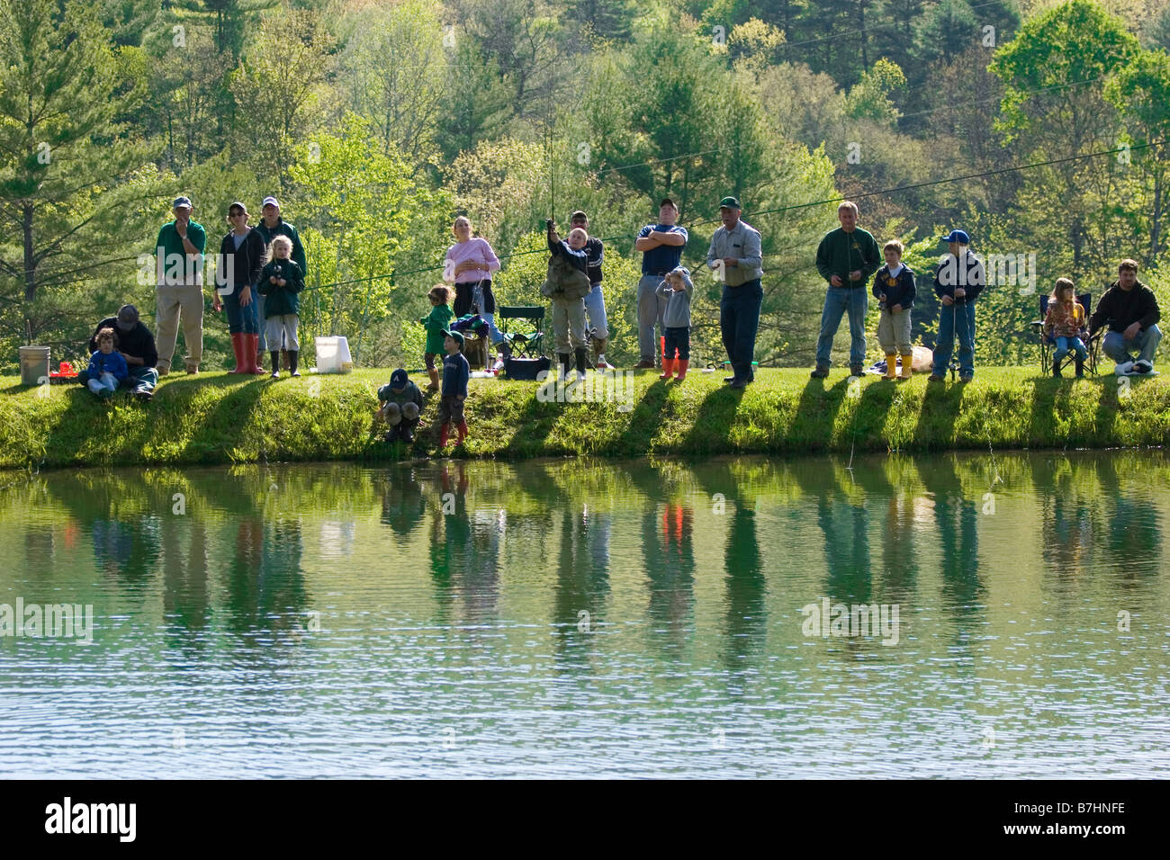 Families gathered around pond for summer morning fishing derby ...