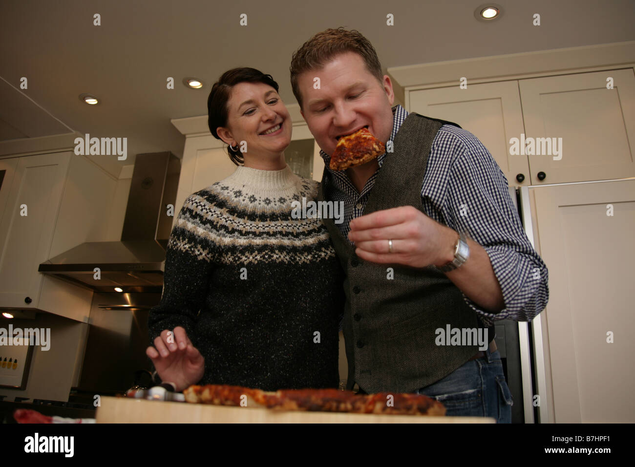 Man eating pizza with wife in the kitchen of their home Stock Photo - Alamy