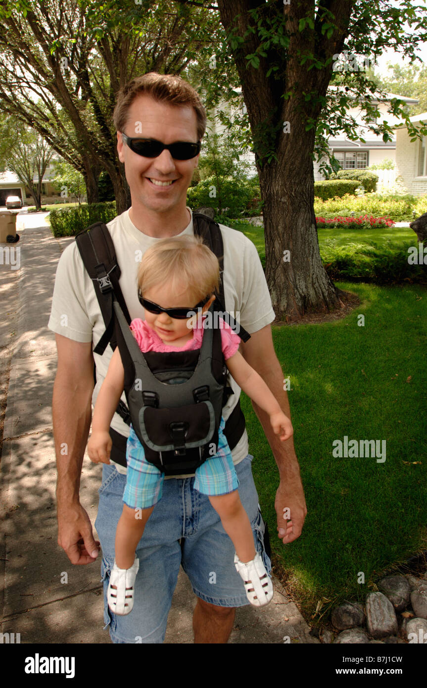 Man walking down street carrying baby in snuggly, Regina, Saskatchewan ...