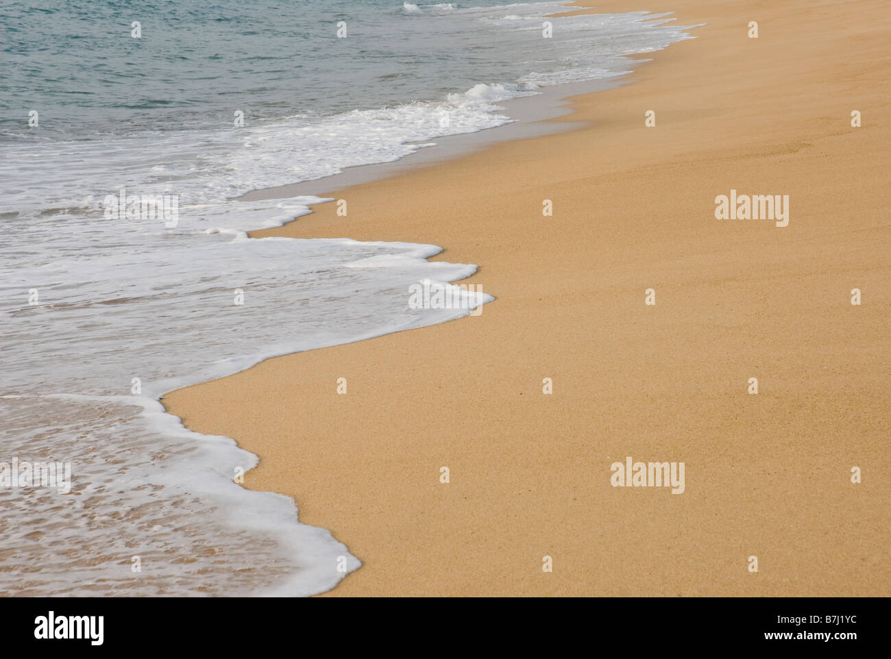 Waves lapping on golden sandy beach Stock Photo - Alamy