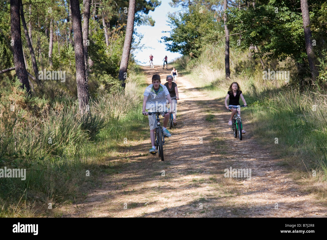 A family enjoy a downhill run through the woods on their bicycles ...