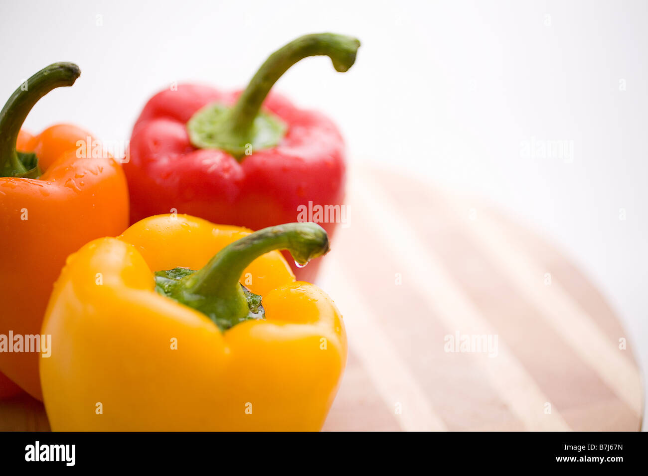 Yellow, orange and red peppers on butcher block cutting board Stock ...