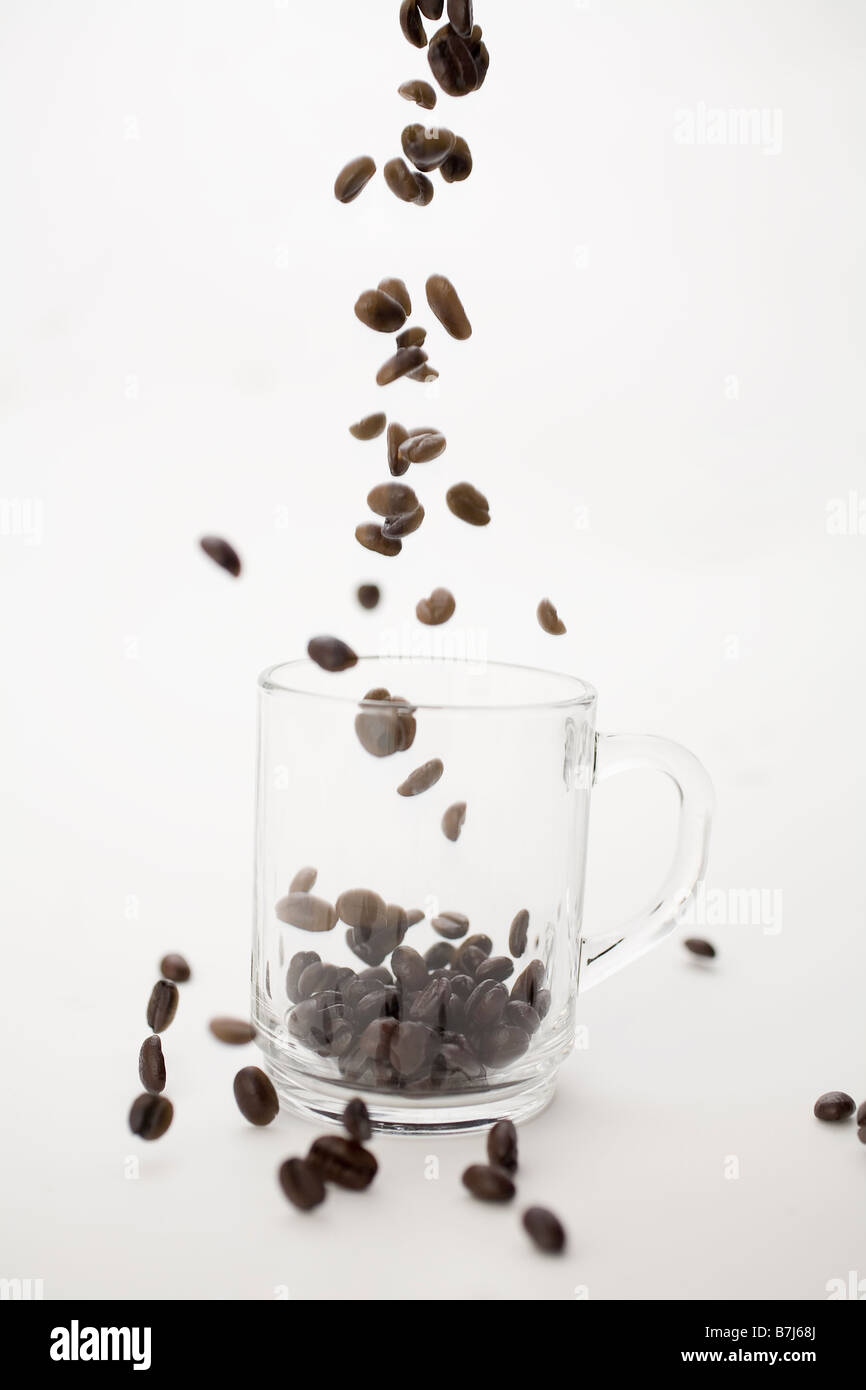 Coffee beans falling into clear coffe cup Stock Photo - Alamy