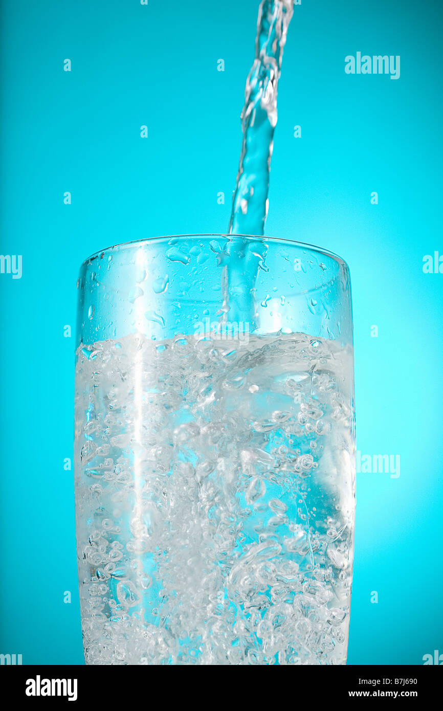 Water pouring into nearly full glass Stock Photo - Alamy