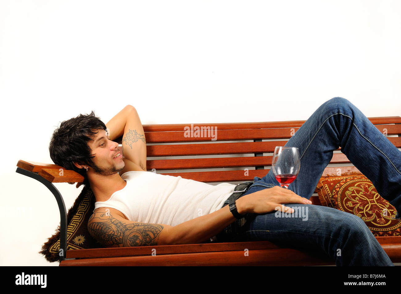 Portrait of a young man reclining over a bench with glass of wine Stock ...