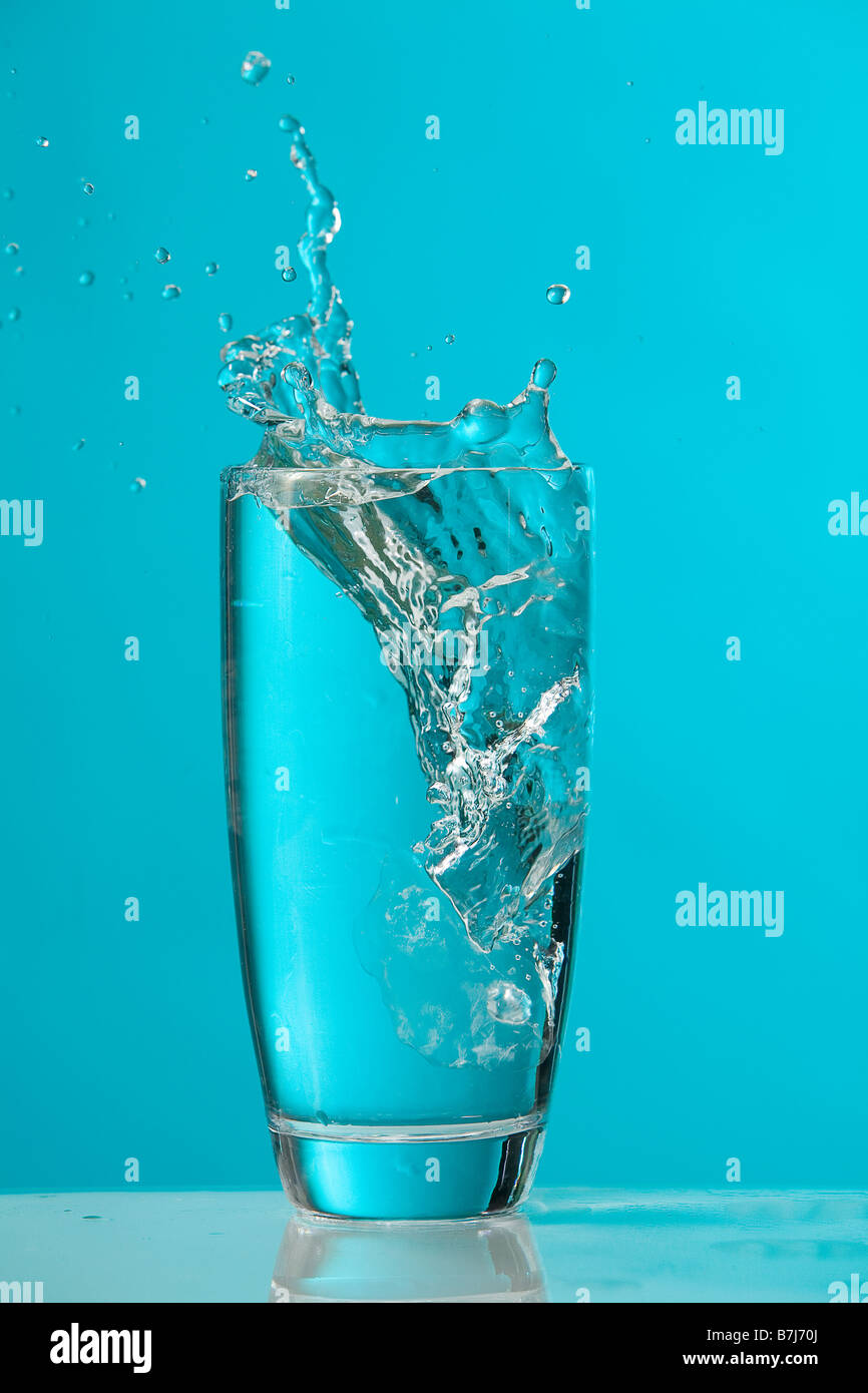 Water splash as ice cube drops into glass of water Stock Photo - Alamy