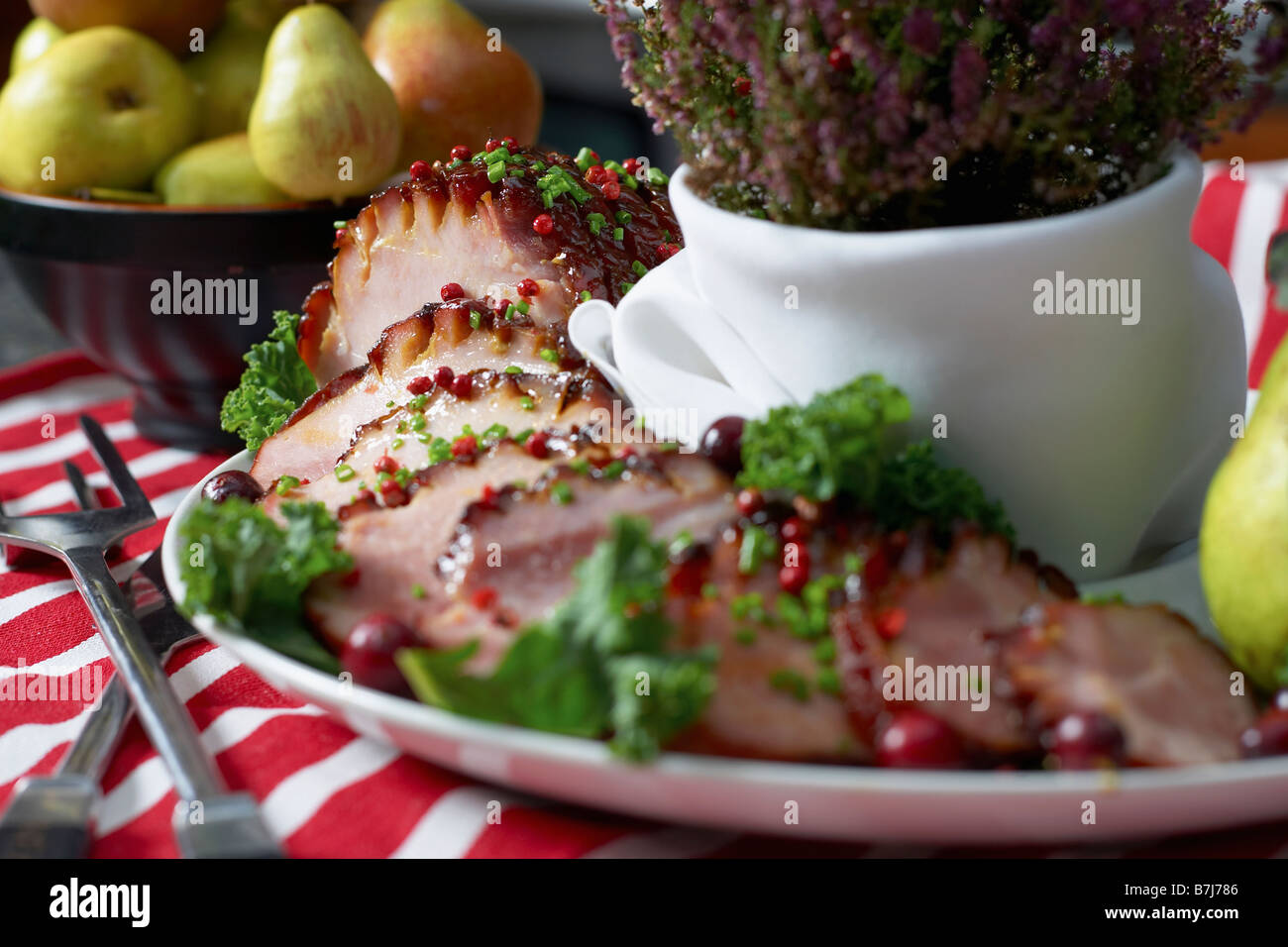 Festive oven roasted ham sliced and garnished with chives and ...